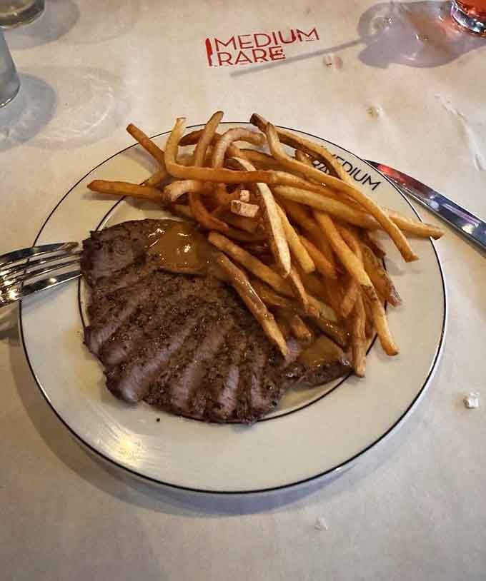 Behold the main event: perfectly sliced steak draped with that legendary sauce, flanked by a mountain of golden fries.