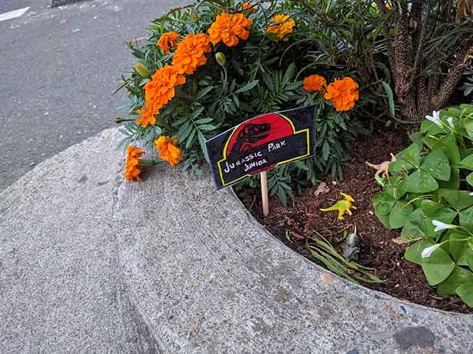 Someone placed a tiny Jurassic Park sign here, because why shouldn't the world's smallest park have its own miniature attractions?
