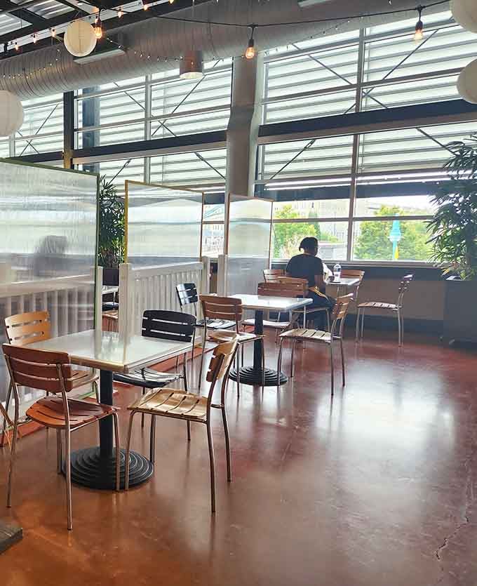 Sunlight streams through industrial windows onto tables where strangers become friends over shared meals and good conversation.