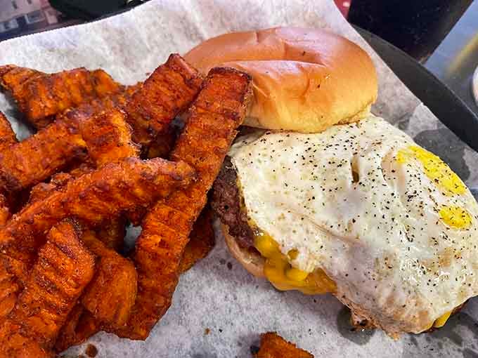 A burger topped with a fried egg and sweet potato fries. Breakfast and lunch finally stopped fighting.
