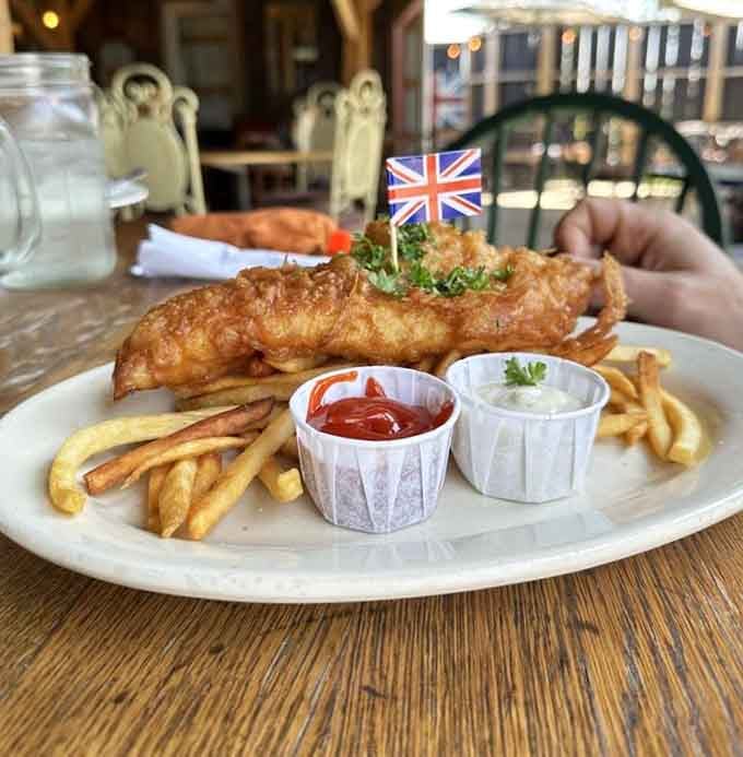 Proper fish and chips arrive with a tiny Union Jack, golden batter crackling with authentic London pride.