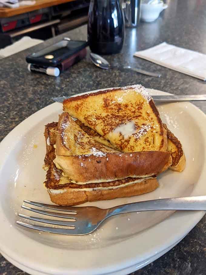French toast so perfectly golden it could win beauty pageants, dusted with powdered sugar like edible snow.