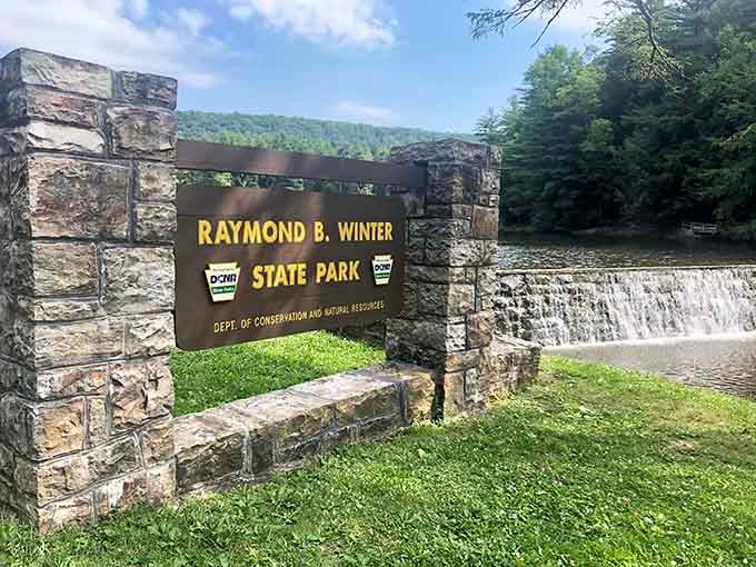 The park entrance welcomes visitors with rustic stone pillars and a cascading waterfall that sets expectations delightfully high.