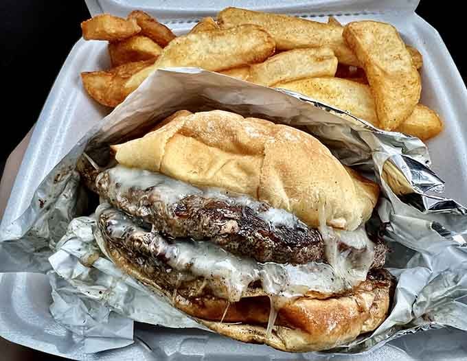 This burger means business, arriving with a cascade of melted cheese and a mountain of golden fries.