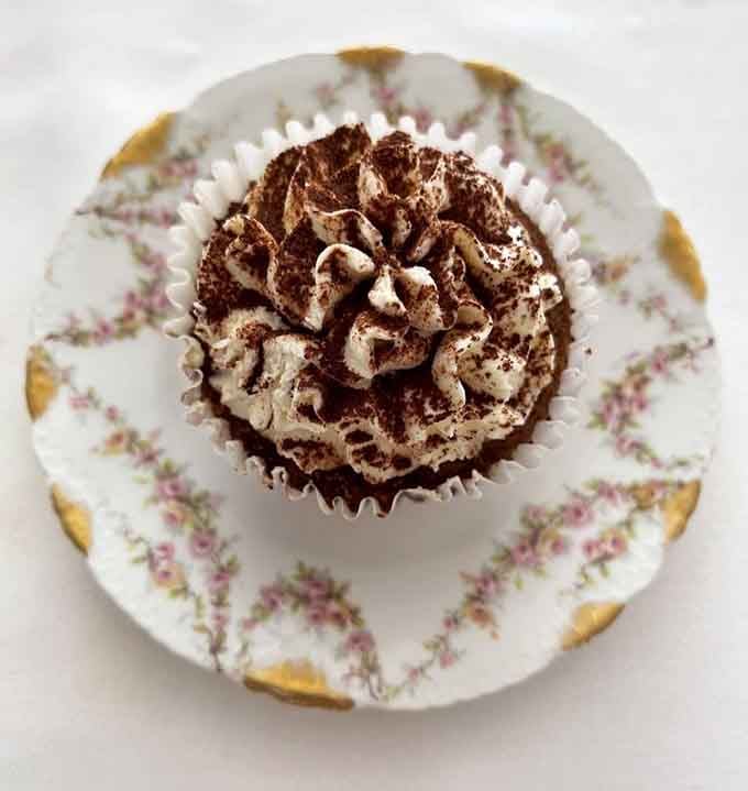 That chocolate cupcake sits on vintage china like it's posing for its own romance novel cover.