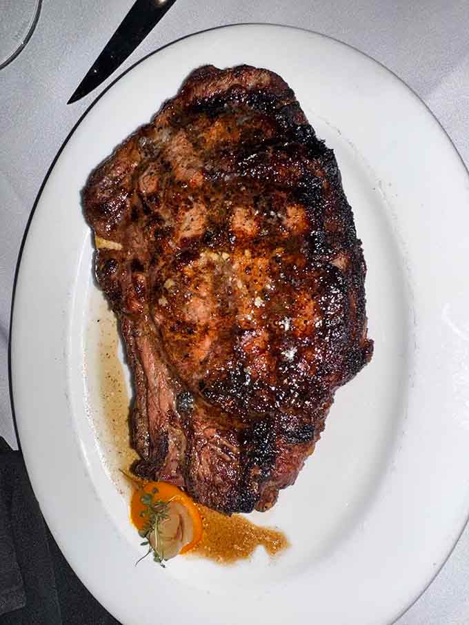 Behold the dry-aged bone-in rib eye, a magnificent slab of beef that practically demands its own zip code.