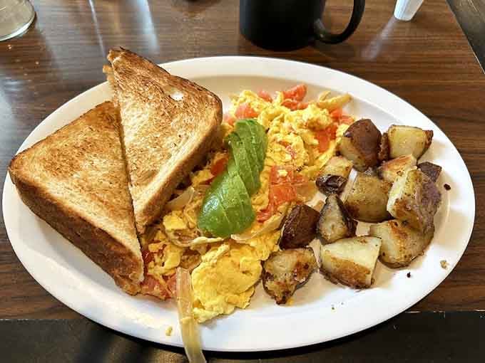 Scrambled eggs with avocado and perfectly crispy home fries: breakfast done right, no apologies needed.