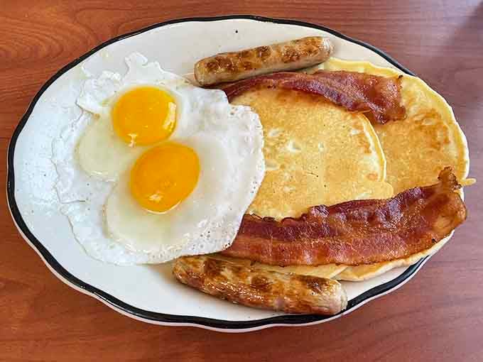 Two sunny eggs, crispy bacon, sausage links, and golden pancakes prove breakfast is the superior meal.