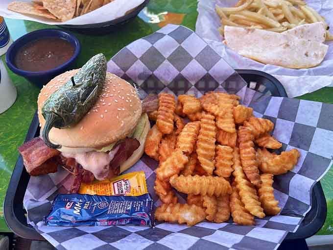 That burger means business, stacked high with toppings and flanked by a mountain of golden crinkle-cut fries.