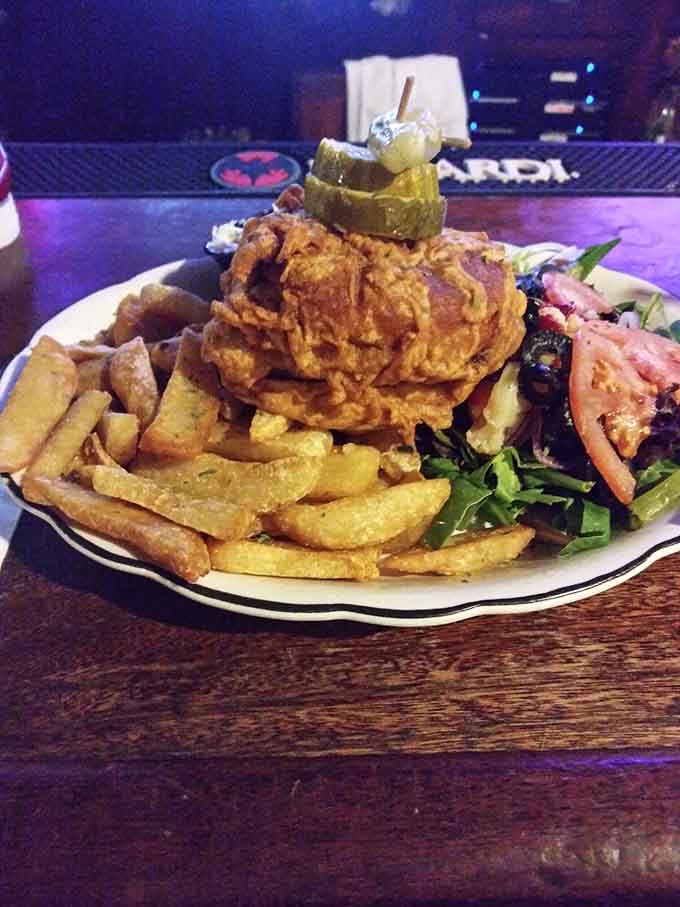 The Death Seat Burger arrives stacked so high it practically requires an engineering degree to figure out the eating strategy.