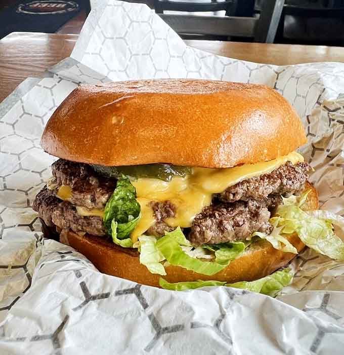 Two juicy patties stacked high with melted cheese cascading down like a delicious golden waterfall between toasted buns.