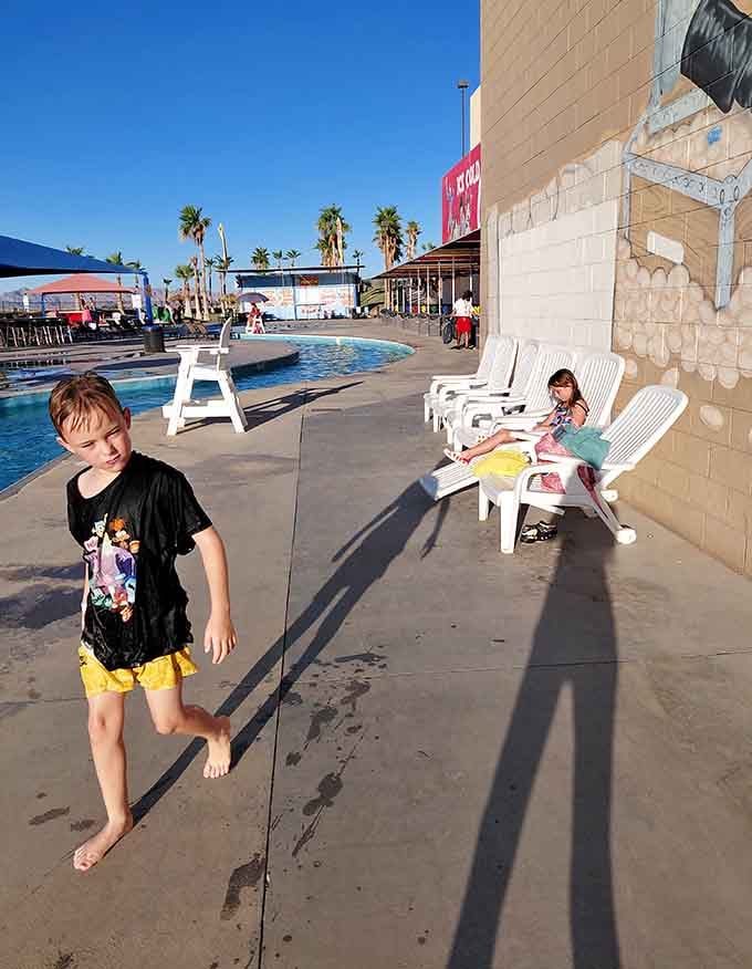Late afternoon shadows stretch across the deck while kids claim their territory on classic white loungers.