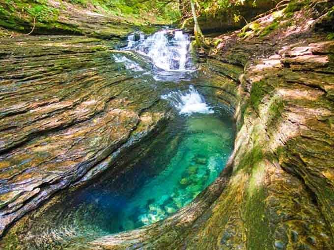 Emerald pool carved into layered rock formations creates nature's own bathtub of pure magic.