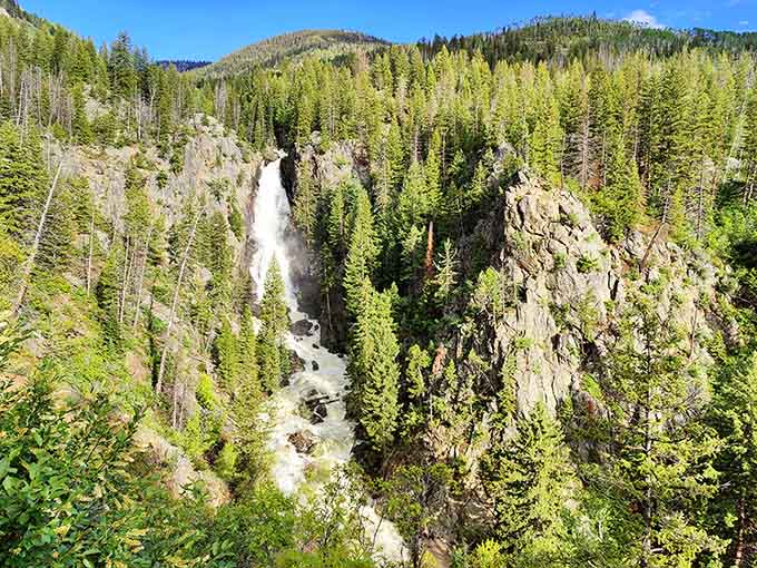 Surrounded by summer's lush greenery, this powerful cascade roars through the rocky gorge with impressive force.