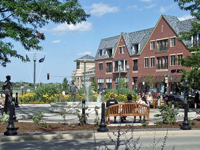 Brick buildings frame a sunny plaza where benches invite conversation, proving that good urban planning creates genuine community connections.