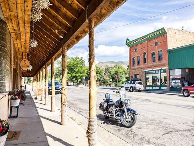 Wooden awnings cast cool shadows while mountain forests rise like a green wall behind downtown shops.