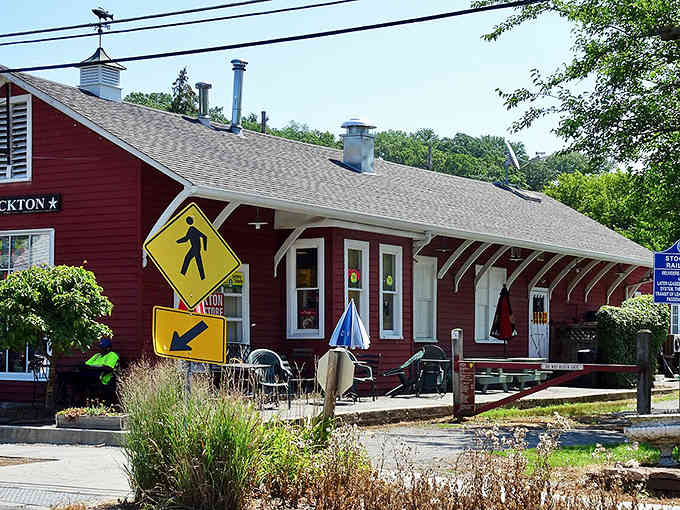Small-town simplicity meets riverside beauty where a single red building anchors an entire peaceful community.