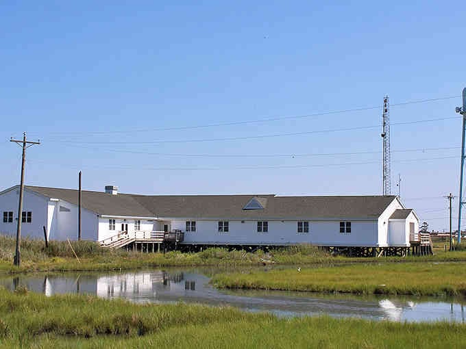 This waterside building sits perfectly still, reflecting in the marsh like it's been here forever.