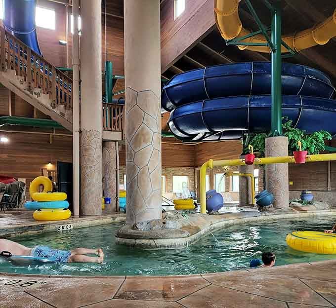 Inside Three Bear Waterpark, massive teal tubes snake through warm lodge air while rustic timber columns give the whole scene a northwoods soul.