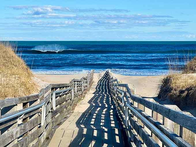 Weathered boardwalks cut through golden dunes leading to endless blue horizons where ocean meets sky perfectly.
