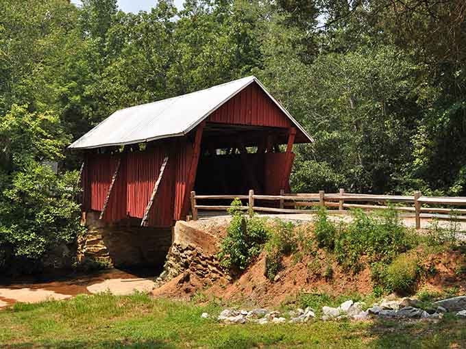 That classic red covered bridge stands proud against summer foliage, looking like a Norman Rockwell painting.