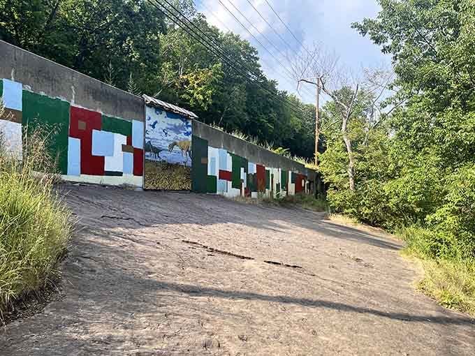 The colorful mural brings prehistoric creatures to life beside the actual footprints they left in what was once soft riverside mud.