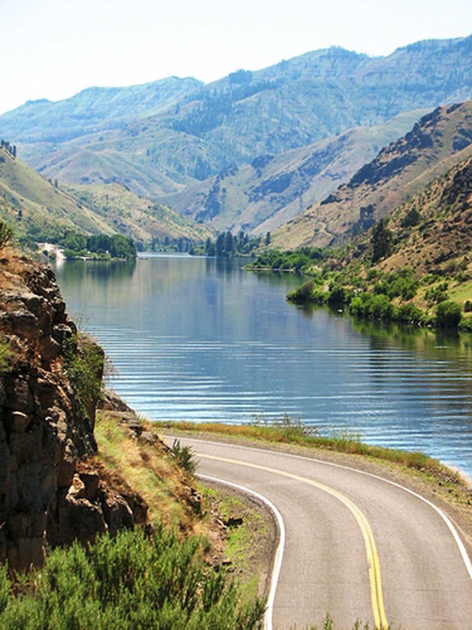 The Snake River glimmers far below while the road hugs cliffs that make your palms sweat just looking.