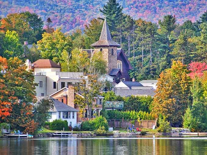 Fall foliage explodes behind the village like nature's own fireworks display reflecting perfectly in the crystal-clear water below.