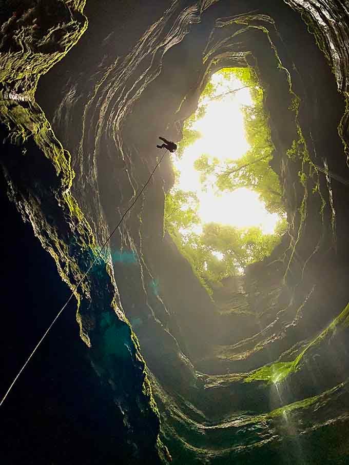 Looking up from the bottom reveals nature's perfect circle, where sunlight and green moss create an otherworldly glow.