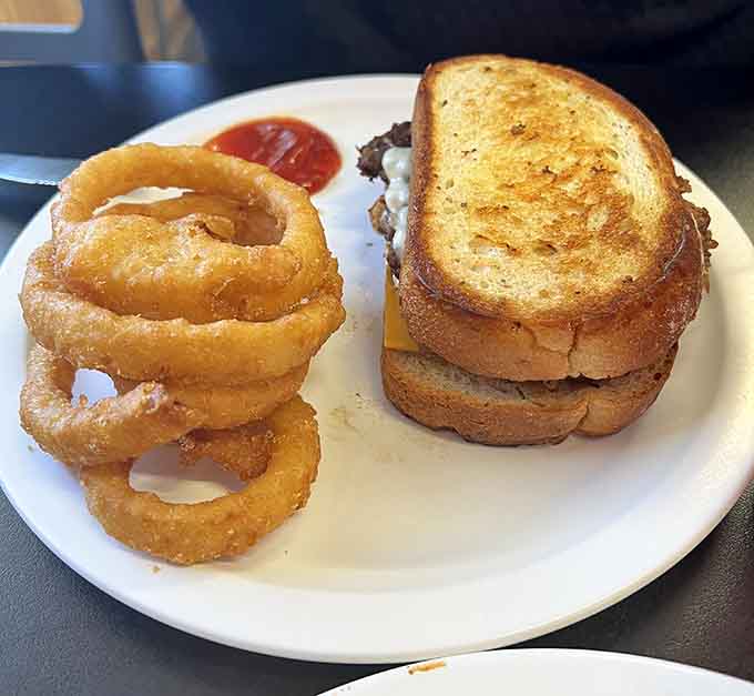 Golden onion rings towering beside a perfectly grilled patty melt is the kind of lunch that makes everything right.