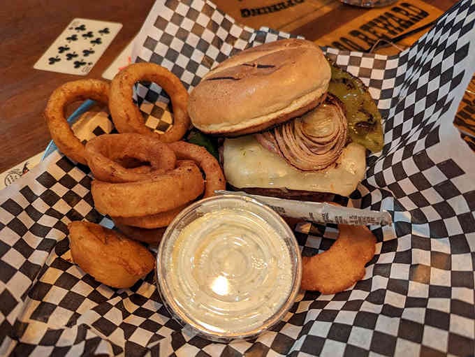 This burger towers like a delicious architectural marvel, paired with onion rings that deserve their own standing ovation.