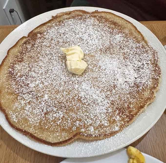 This plate-sized pancake dusted with powdered sugar could double as a delicious landing pad for butter.