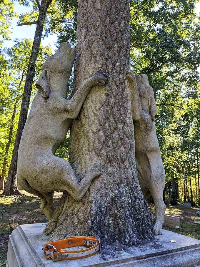 Two concrete hounds stand eternal guard, their weathered forms wrapped around a tree like they're still on the hunt.