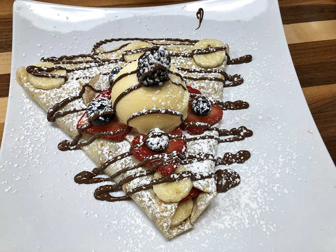 Fresh berries, sliced fruit, and chocolate artistry make this crepe look almost too beautiful to eat. Almost.