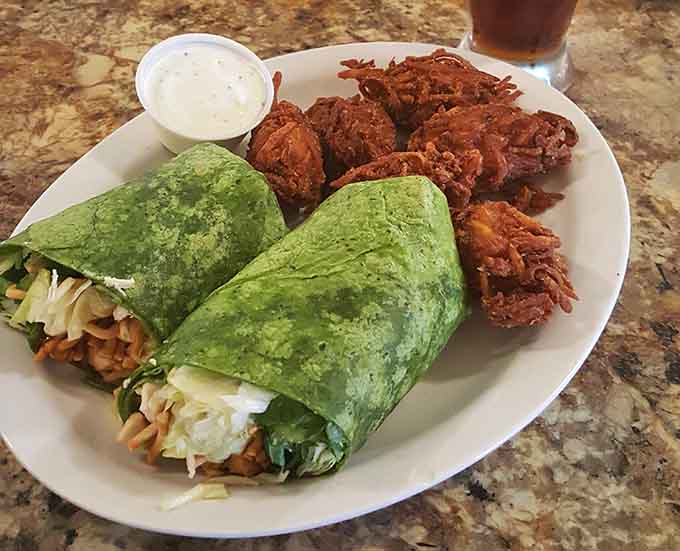 That vibrant green wrap paired with crispy onion rings proves lunch here is just as impressive as breakfast.