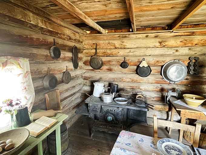 Cast iron pans line the log walls like medals of honor in this pioneer kitchen that knew real work.