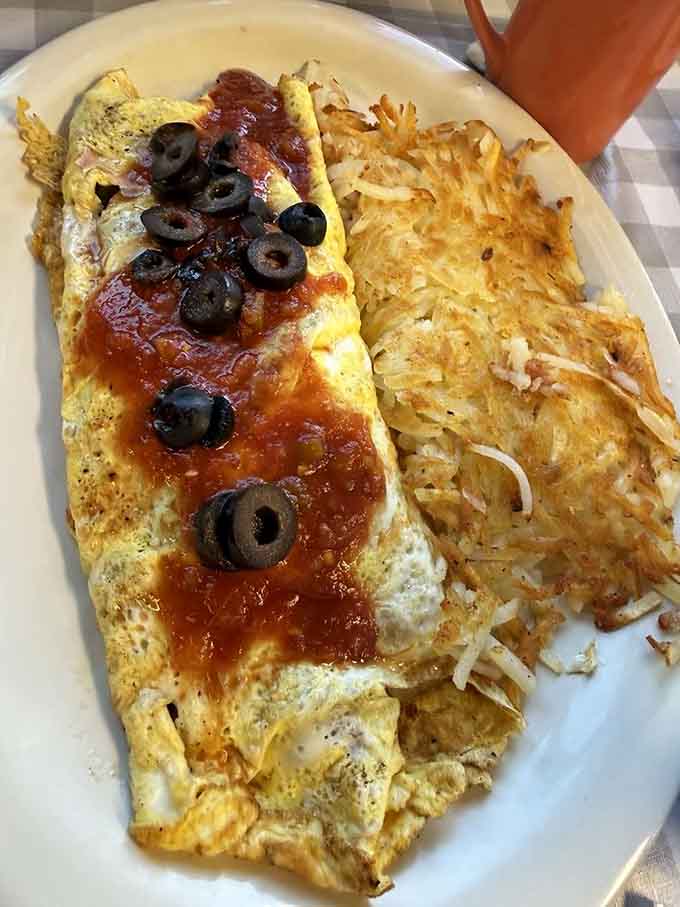 That omelet is loaded with salsa and olives while hash browns crisp up like edible gold next door.