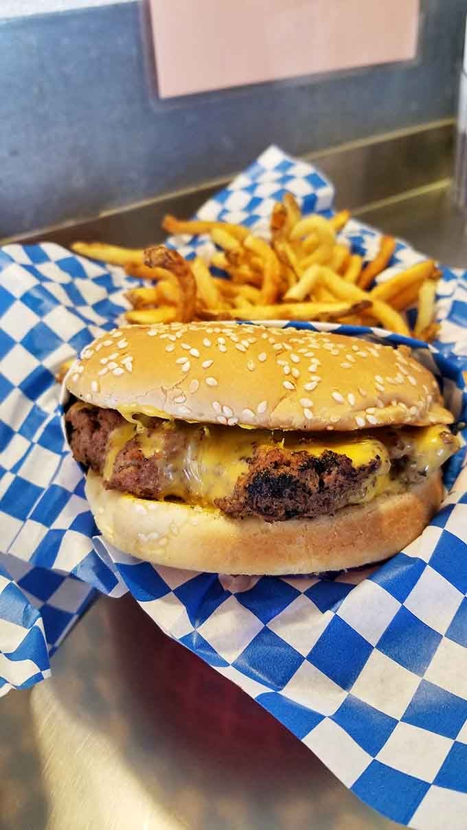 That sesame seed bun cradles a burger so juicy it practically requires a lifeguard, with fries standing golden guard.