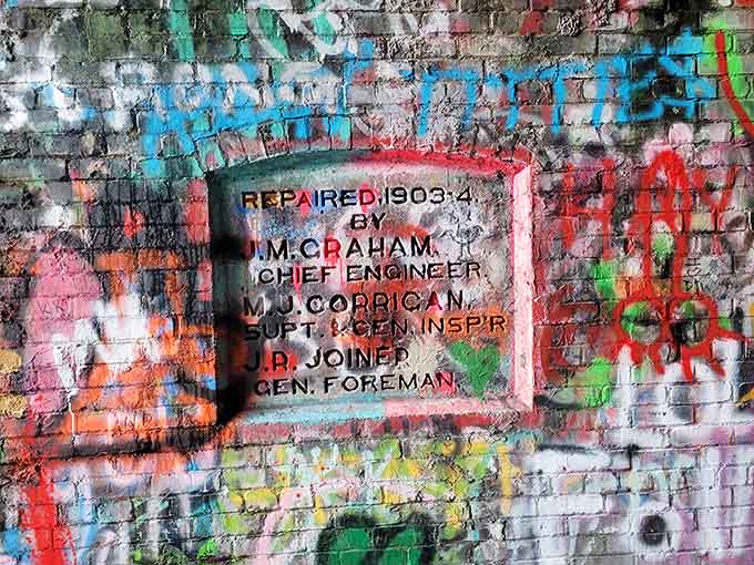 Historical plaques on the brick walls tell stories of repairs and engineers, though they're now competing with decades of colorful additions.