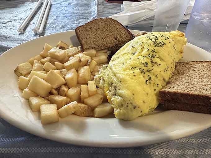 A fluffy omelet so perfectly golden it practically glows, flanked by crispy potatoes and toast for backup.