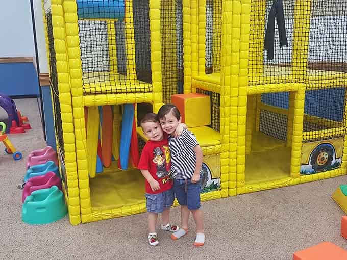 Two buddies posing by the yellow foam structure perfectly capture that universal joy of finding your playground partner in crime.