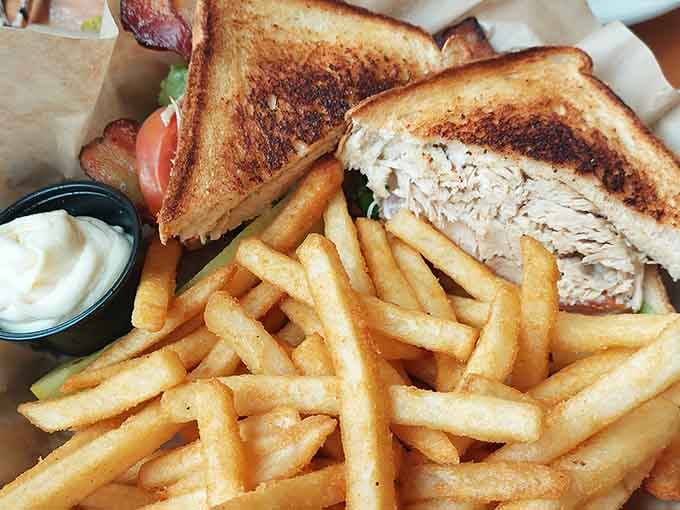 This turkey club is stacked so high it practically needs its own zip code, served with fries that disappear faster than common sense.