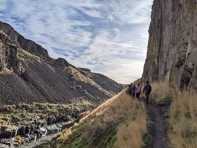 Hikers tracing a path along basalt walls so tall they make skyscrapers look like they're not even trying.
