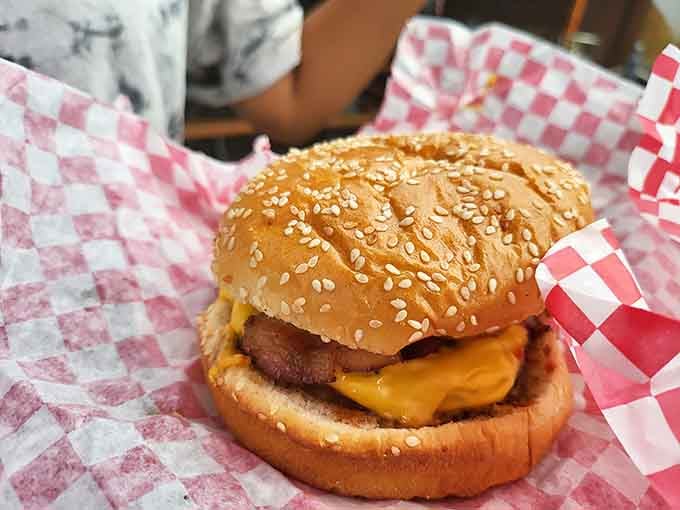 A sesame seed bun cradling a burger topped with onion rings proves that sometimes excess is exactly right.