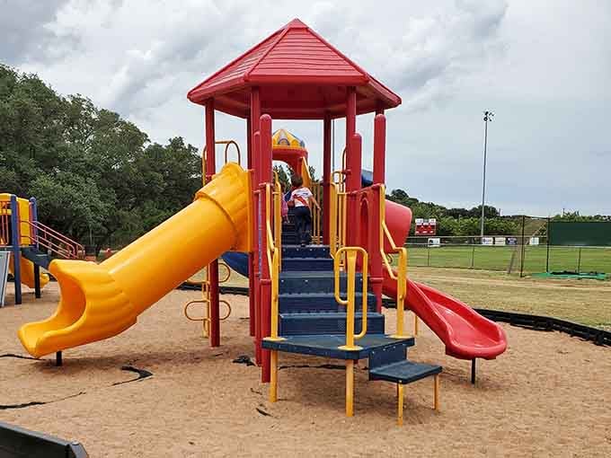 Bright playground equipment stands ready for kids to burn energy while parents actually relax for once.