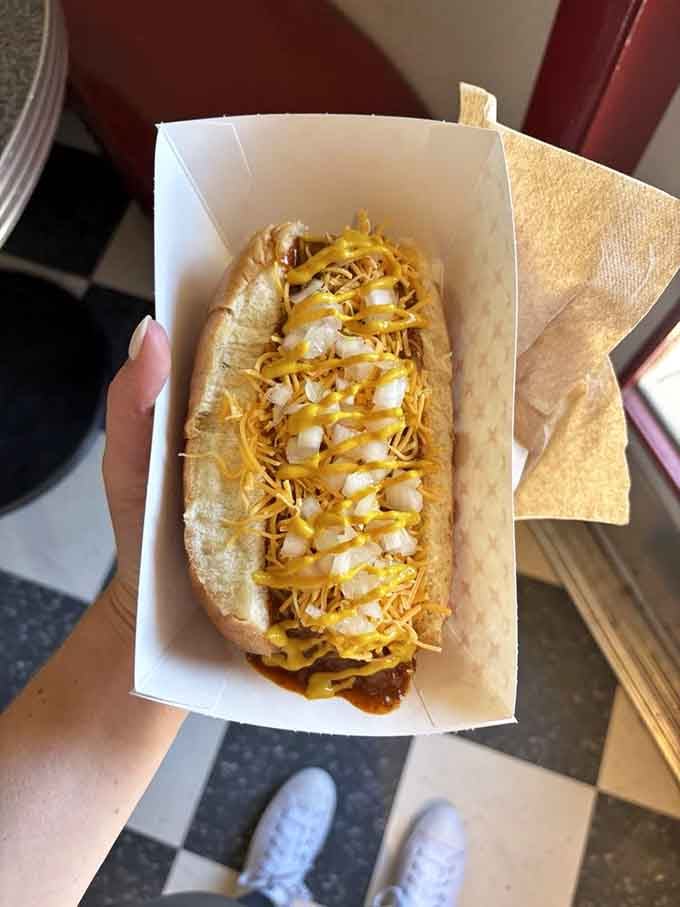Red chili cascading over a coney dog like lava from a delicious volcano, ready to ignite your taste buds.