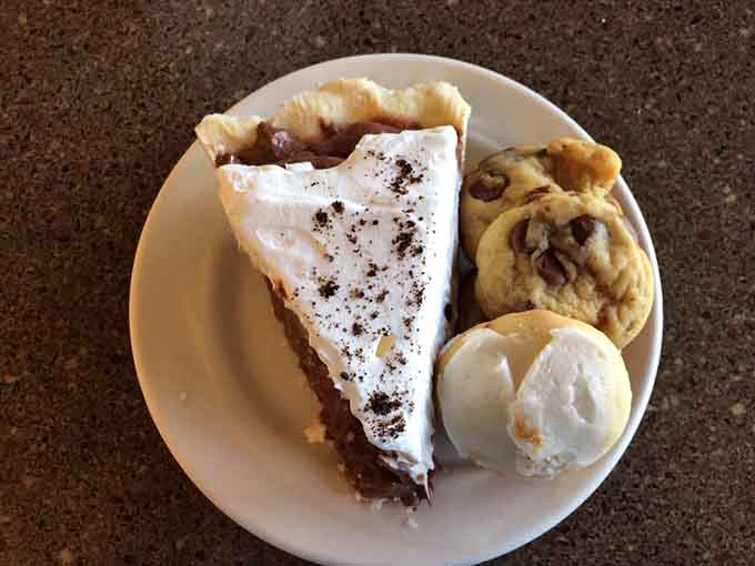 Chocolate cream pie arrives with a bonus cookie because sometimes life gives you exactly what you need and more.