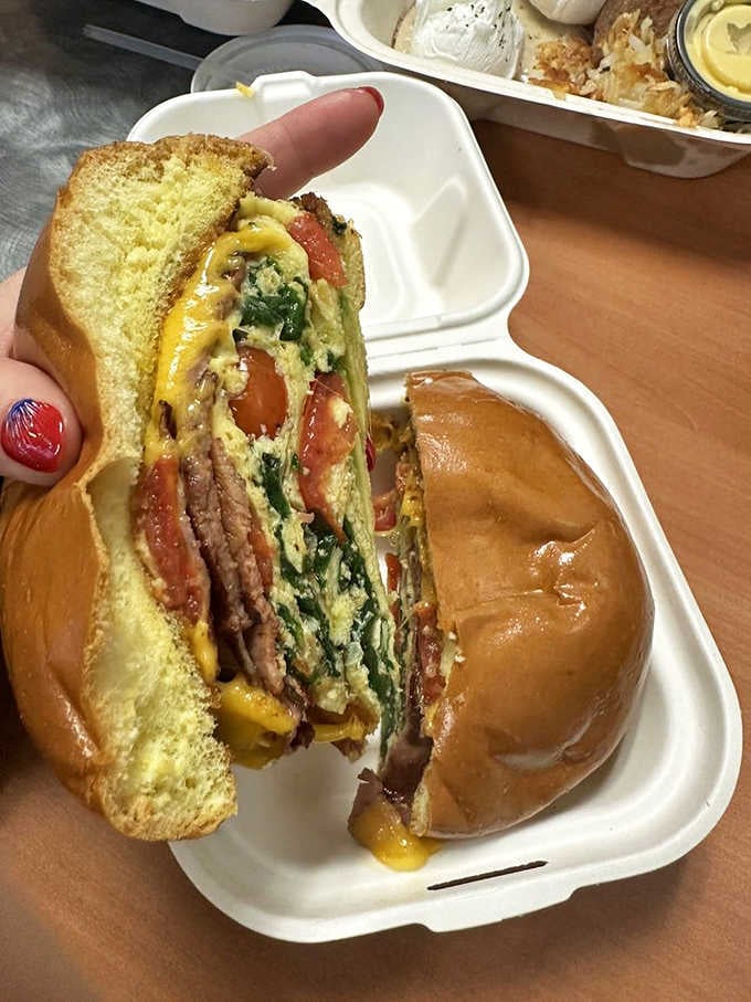 This loaded breakfast sandwich isn't messing around, stacked high with eggs, meat, and melted cheese on toasted bread.