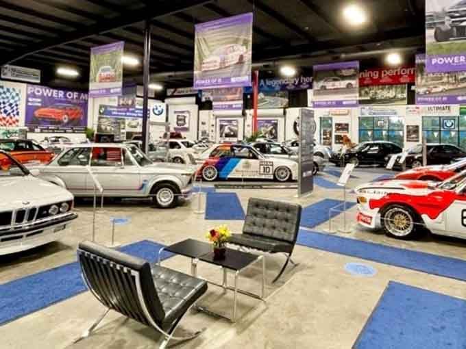 Modern chairs face classic racing machines, creating the perfect spot to contemplate automotive history in air-conditioned comfort.