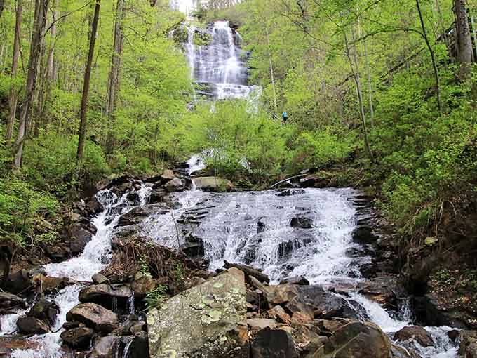 Spring greenery frames the lower cascades of this towering waterfall as it tumbles over moss-covered rocks and boulders.